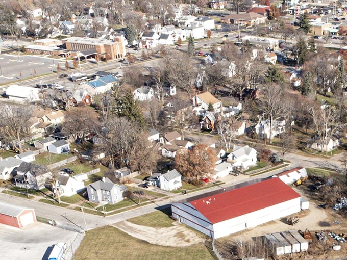 Aerial view of Owosso's charming neighborhoods with tree-lined streets and a distinctive red-roofed building.