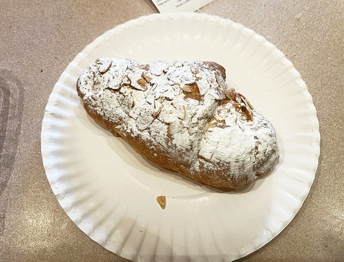 This almond croissant wears its powdered sugar like a winter coat, promising layers of buttery pastry and rich almond filling within.