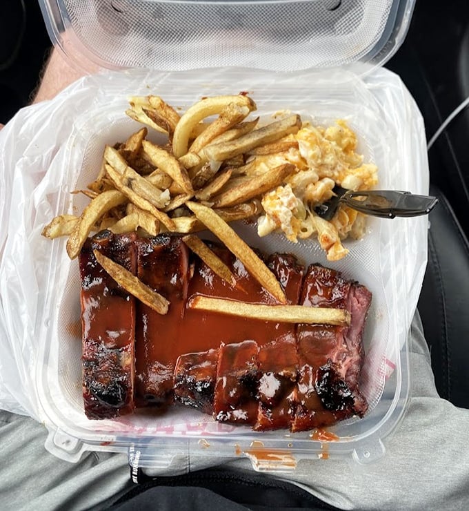 These ribs glisten like mahogany treasures, each one promising that perfect bite where meat meets smoke meets sauce meets bliss.