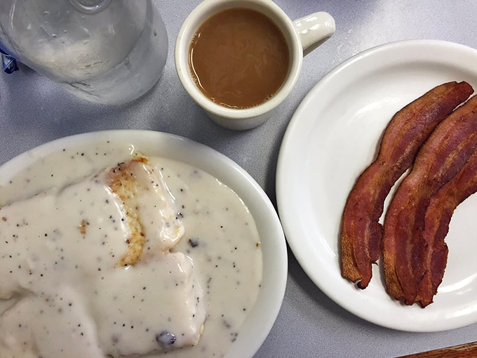 Biscuits swimming in creamy pepper gravy alongside perfectly crisped bacon – the breakfast of champions and the cure for whatever ailed you yesterday.