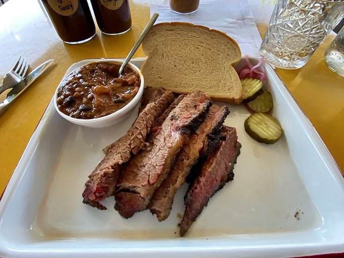 Brisket sliced to perfection reveals that coveted pink smoke ring, while beans stand by as loyal companions in this classic barbecue tableau.