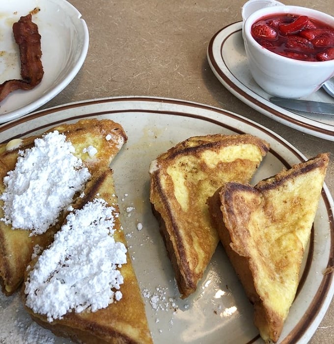 French toast dusted with powdered sugar like the first snow of winter, with a side of what appears to be homemade berry compote. Breakfast royalty.