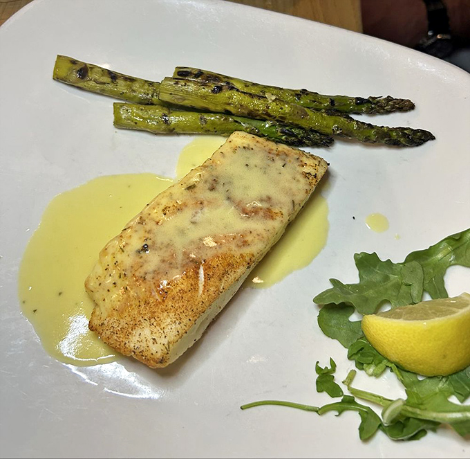 Perfectly grilled halibut rests in a pool of delicate beurre blanc alongside charred asparagus. Simple perfection that lets quality ingredients shine.