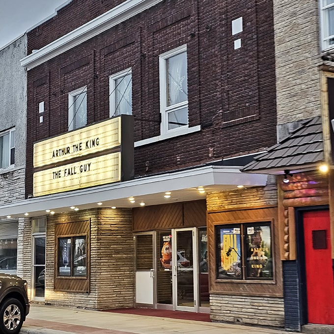 The Palace Theatre marquee glows with promise as dusk approaches. In small towns, Friday night movies still feel like events worth dressing up for.