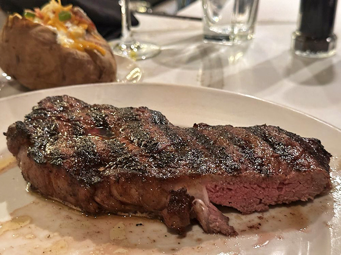 The NY Strip reveals its perfect pink center like a sunset breaking through storm clouds&mdash;a carnivore's masterpiece worth every bite.