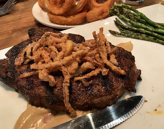 A ribeye so perfectly charred it should have its own Instagram account, topped with crispy onion straws that add textural jazz hands.