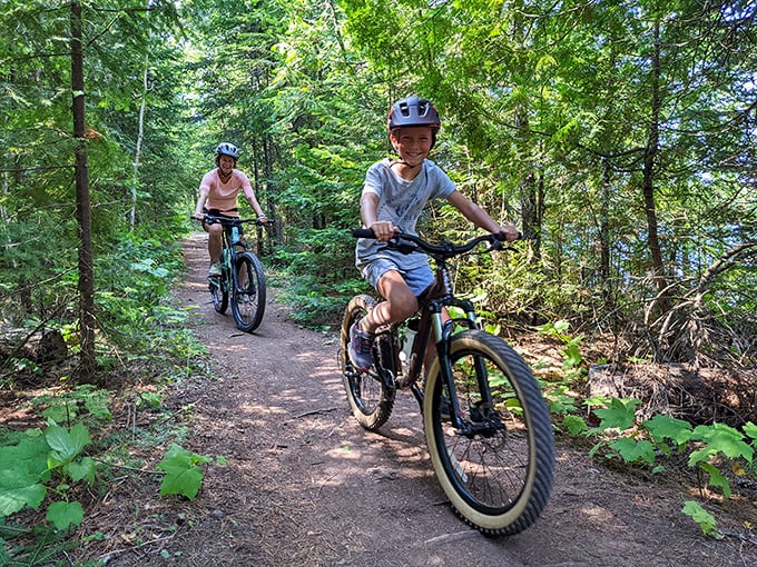 Family mountain biking through Copper Harbor's lush forest trails &ndash; where screen time surrenders to green time.