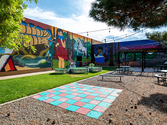 This vibrant mural space transforms an ordinary corner into an outdoor living room, complete with string lights and a life-sized game board.