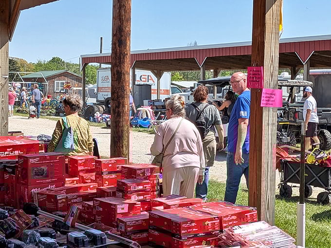 The universal dance of flea market negotiation unfolds beneath the red Milwaukee tool banner. The art of the deal is alive and well.