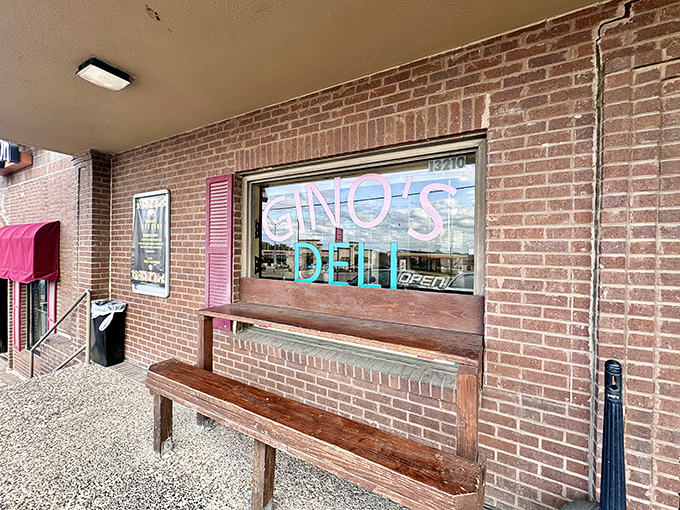 This cozy local deli features a classic brick exterior and a welcoming wooden bench, perfect for enjoying a delicious midday sandwich.