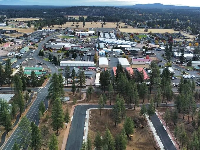 An aerial view showcases Sisters' perfect blend of small-town charm and outdoor adventure, nestled among towering pines and open meadows.