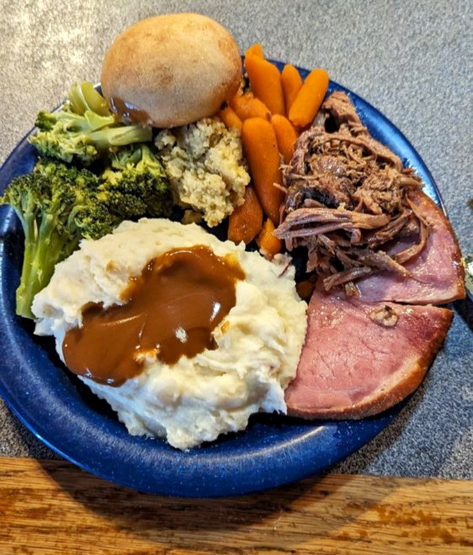 A blue plate special that would make your grandmother nod in approval—mashed potatoes, gravy, ham, and vegetables playing their supporting roles perfectly.