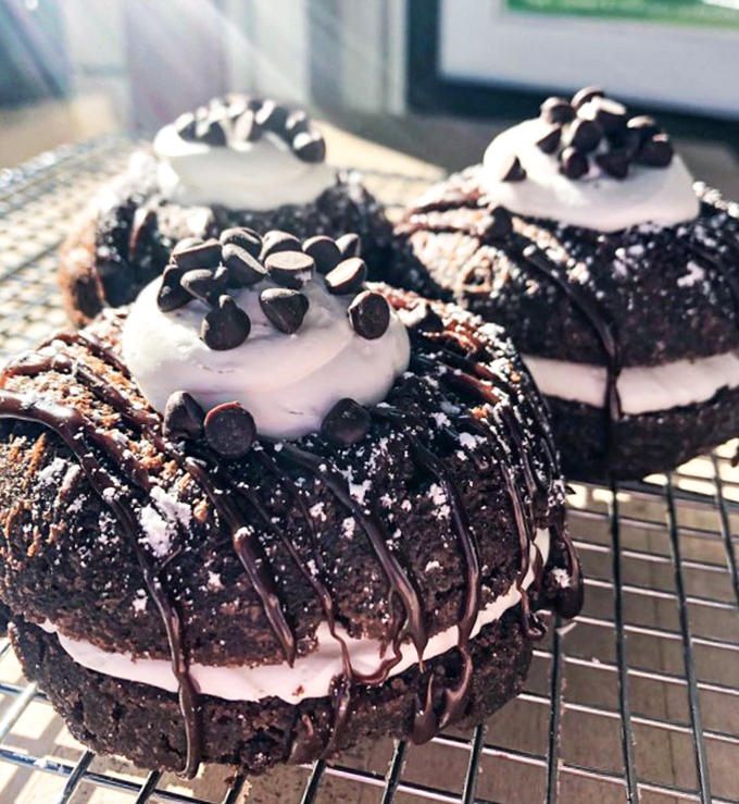 These chocolate donuts with vanilla cream and chocolate chips look like they graduated from dessert university with highest honors.