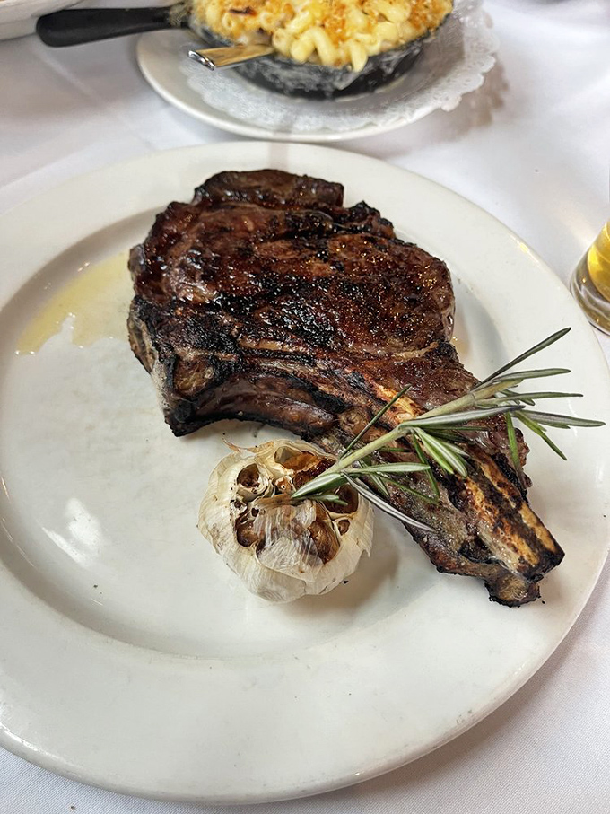 A cowboy steak with a char that would make campfire cooks jealous, accompanied by roasted garlic that's mellowed into sweet submission.