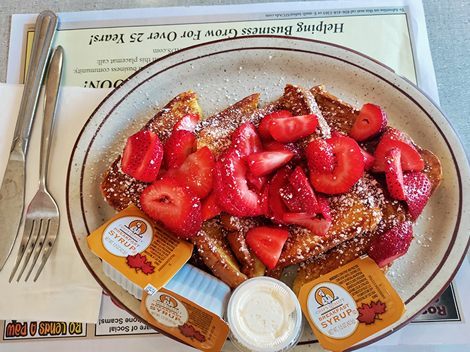French toast that makes you question every sad, soggy version you've ever made at home, crowned with fresh strawberries and powdered sugar snowfall.