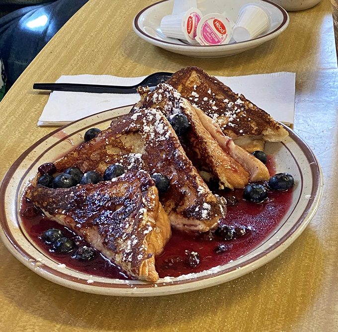 French toast that doesn't just say good morning—it serenades you with blueberries, a berry compote, and enough powdered sugar to make your dentist wince.
