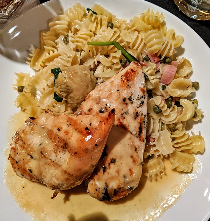 Grilled chicken resting on a bed of pasta with capers&mdash;like a Mediterranean vacation that fits perfectly on your fork.