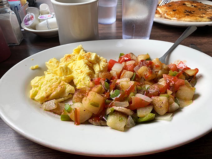 Scrambled eggs meet their soulmate—home fries with personality, dressed up with peppers and onions like they're heading to a potato prom.