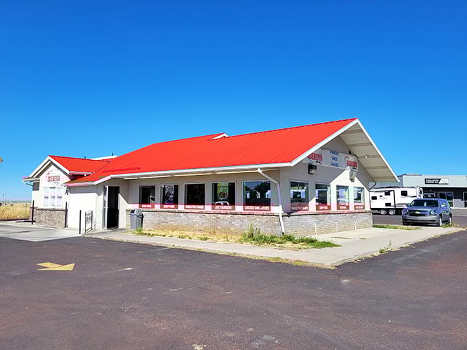 The bright red roof of Iceberg Drive Inn beckons like a lighthouse for the hungry, promising frosty treats in a sea of highway asphalt.