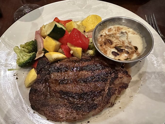 A ribeye that's earned its grill marks honestly, served with colorful vegetables that aren't just there for show. That little cup of sauce? Liquid gold.