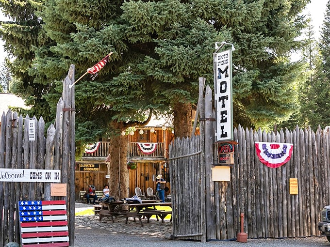 The Stockade Motel embraces its Wild West aesthetic with rustic charm and American flags, offering weary travelers a frontier-themed respite among the pines.