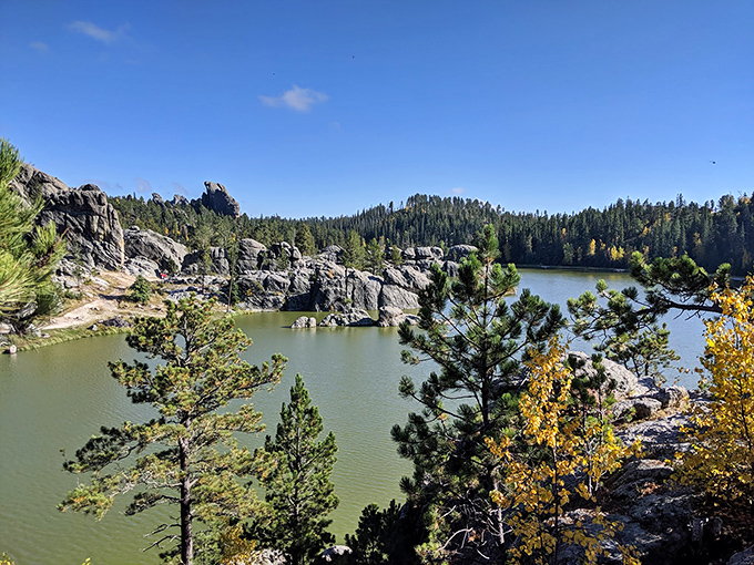 Nature's masterpiece: rocky outcrops embrace emerald waters while autumn's golden touch hints at the changing seasons.