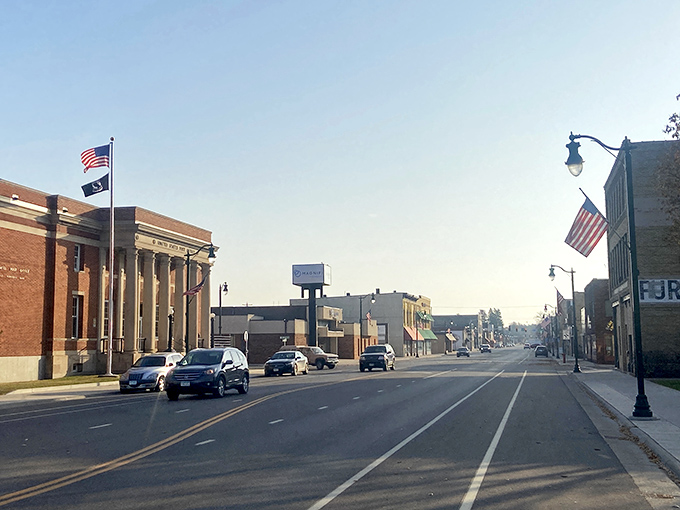 Little Falls' quiet main street showcases its affordable small-town appeal with historic buildings, American flags, and minimal traffic&mdash;perfect for fixed-income living.