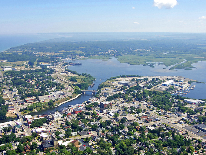 Aerial view of Manistee where the river meets Lake Michigan, showcasing affordable waterfront living and charming downtown.