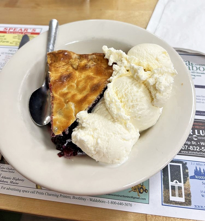 Blueberry pie à la mode—Maine's official dessert diplomacy. Two scoops of vanilla ice cream melting into wild blueberry bliss.