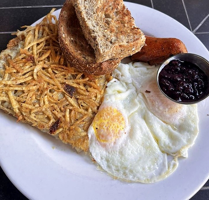 Breakfast perfection: sunny-side up eggs with hash browns so crispy they practically sing, toast standing at attention, and a side of jam for sweet balance.