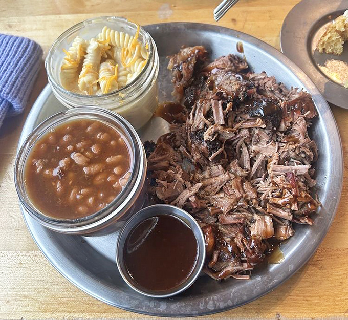 A barbecue plate that hits all the right notes: tender pulled meat, smoky beans, creamy mac and cheese, and that essential side of sauce.