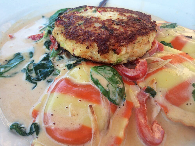 This isn't just a crab cake – it's the reason people cross county lines, sitting pretty atop a creamy vegetable medley that makes vegetables worth eating.