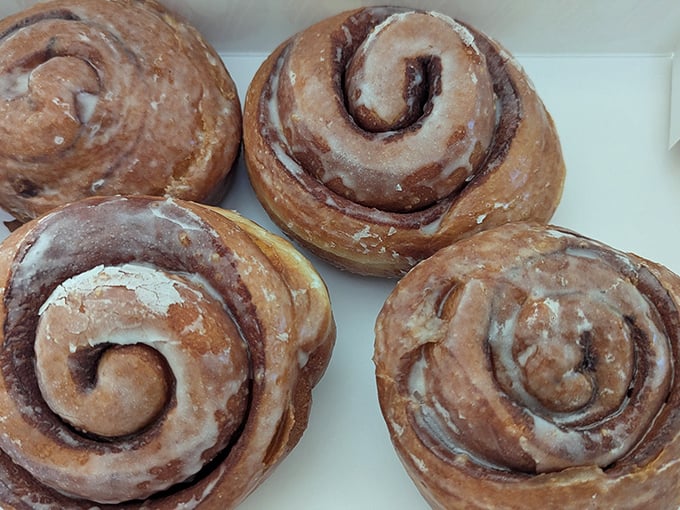 Cinnamon rolls that spiral like galaxies of butter and spice. The icing melts slightly into the warm dough, creating little rivers of sweetness.