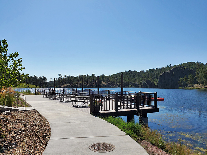 This lakeside dock isn't just a place to sit—it's nature's front-row seat where the Black Hills perform their daily reflection concert.