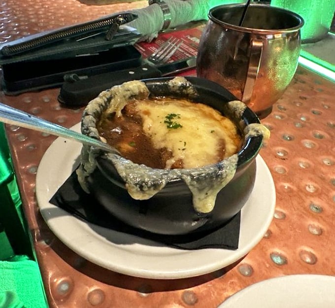 The French onion soup arrives with cheese cascading over the sides like lava from a delicious volcano. Spoon-breaking crust included.