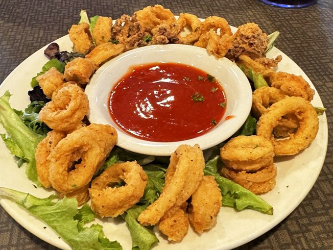Golden-fried calamari rings arranged like a delicious crown around that vibrant marinara dipping sauce&mdash;crunchy perfection awaits.