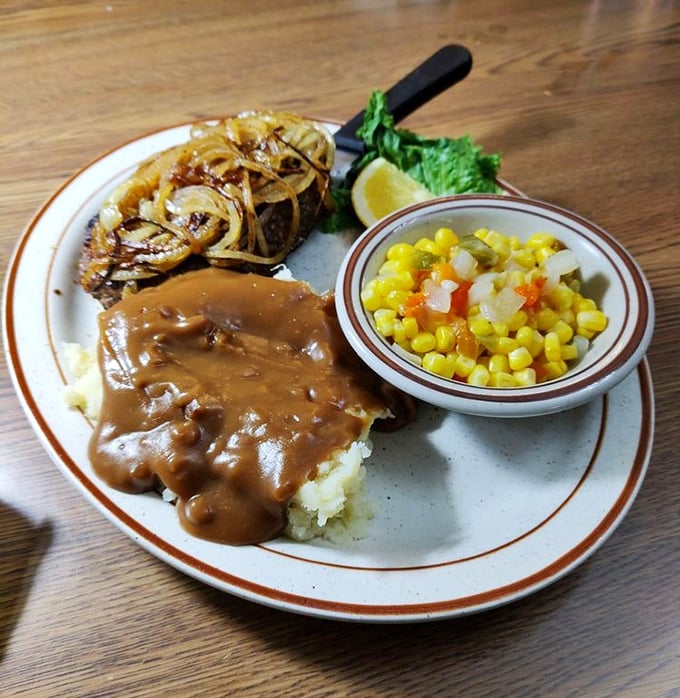 Comfort on a plate: tender beef smothered in savory gravy alongside buttery mashed potatoes and sweet corn medley.