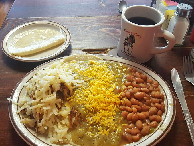 The Cowboy Cafe coffee mug stands guard over a plate where pinto beans, rice, and green chile sauce create New Mexico's answer to breakfast bliss.