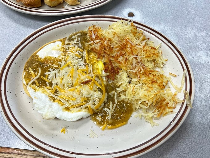 Breakfast alchemy at its finest – eggs smothered in green chile sauce and crowned with perfectly crispy hash browns that somehow manage to be both delicate and substantial.