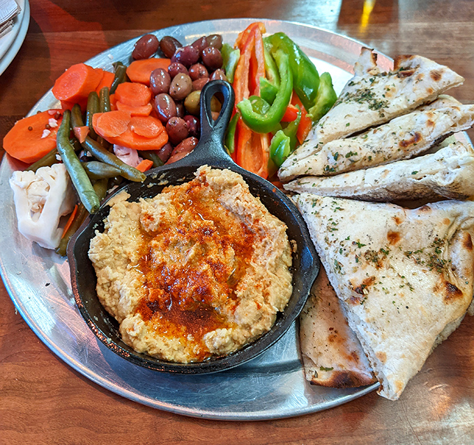 The hummus platter arrives like an edible color wheel - smoky dip surrounded by vibrant vegetables and warm pita triangles.