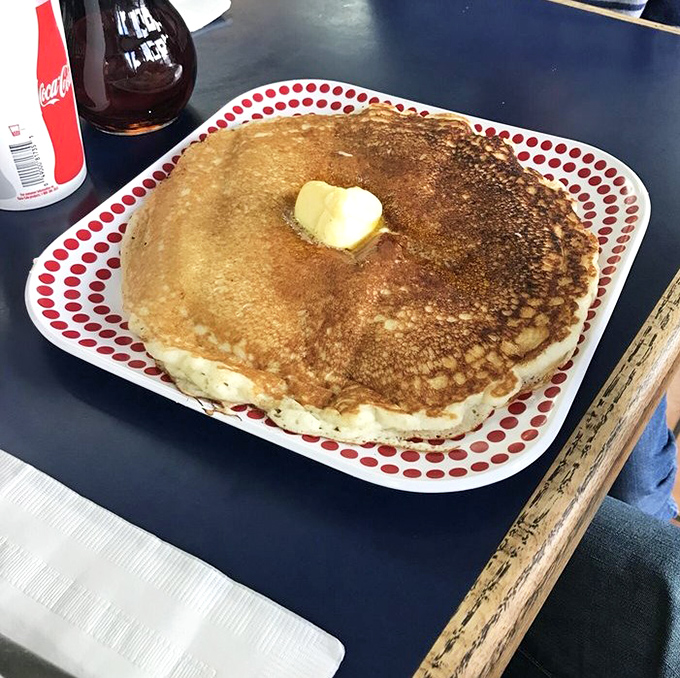A pancake so perfect it deserves its own ZIP code. Golden-brown, plate-sized, and waiting for that slow cascade of maple syrup.