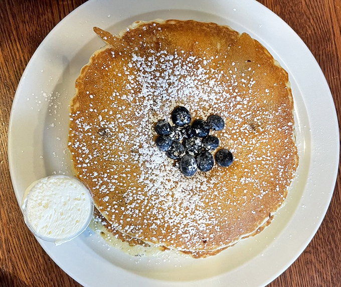 This pancake isn't just a breakfast &ndash; it's a canvas, dusted with powdered sugar and adorned with blueberries that look hand-placed by breakfast artists.