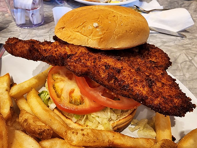 The breaded pork tenderloin sandwich that's having an identity crisis as a small country. Those golden-fried edges extending beyond the bun are pure Midwestern poetry.