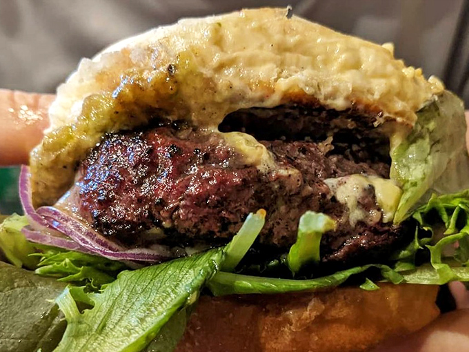 Behold the burger in its natural habitat&mdash;charred exterior, juicy interior, nestled in a bun that knows its supporting role perfectly.