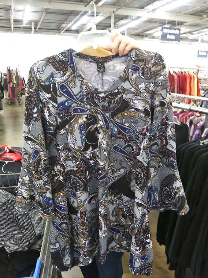 A paisley-patterned blouse with blue accents hangs patiently, waiting for its perfect match in a fashion-forward thrifter.