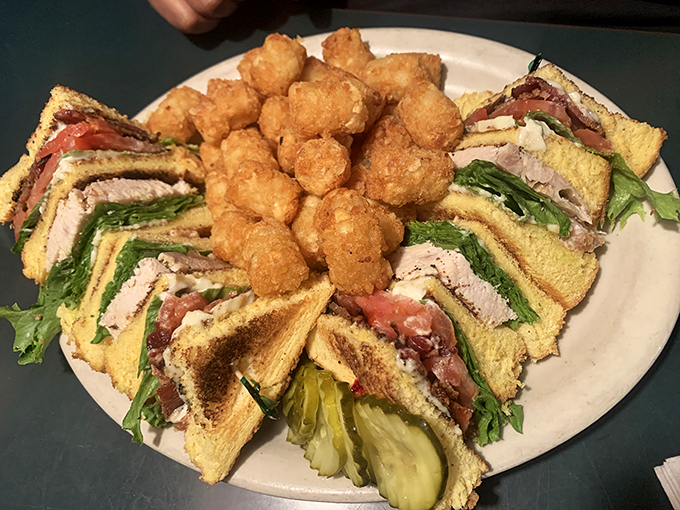 A club sandwich that towers like the Space Needle, surrounded by golden tater tots that deserve their own fan club.