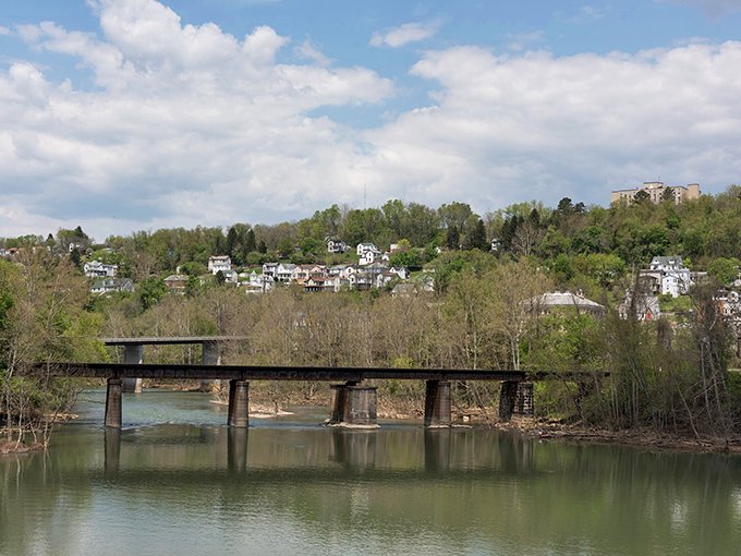 The Tygart River flows peacefully under an old railroad bridge, offering scenic views that would cost a fortune in property values elsewhere.