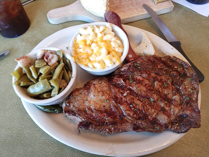 A steak that's been kissed by fire and blessed by seasoning, accompanied by green beans and mac and cheese that refuse to be overshadowed.