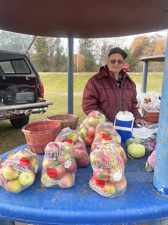 The vendor's weathered hands tell stories of harvests past as he offers up bags of orchard-fresh apples&mdash;Wisconsin's autumn bounty displayed with quiet pride.