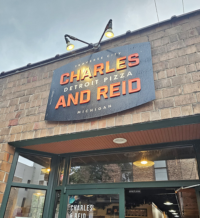 Brick walls and warm lighting create the perfect backdrop for Detroit-style pizza perfection. The sign promises a serious pizza experience.